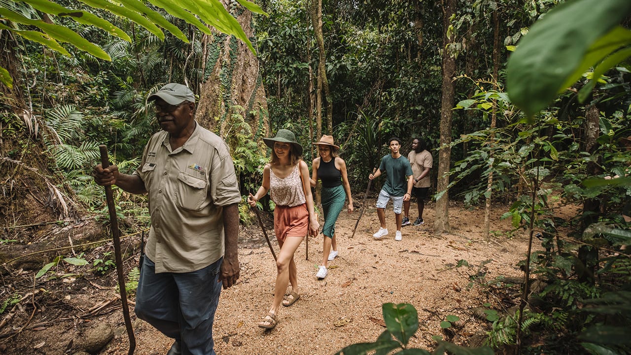 delegates walk through forrest with an Indigenous guide | C&IT World